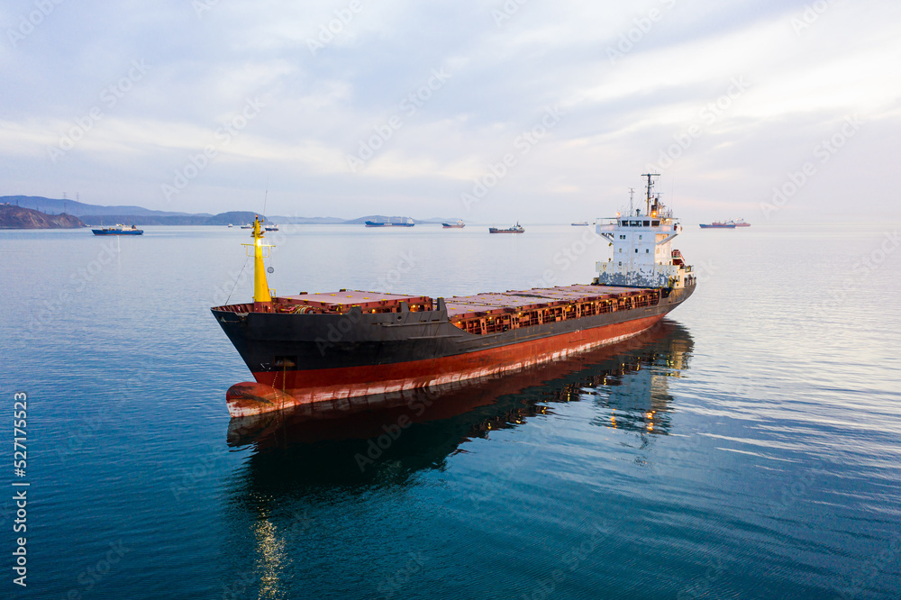 Bulk carrier ship at anchor at sunset, aerial view. Bright sunny path ...