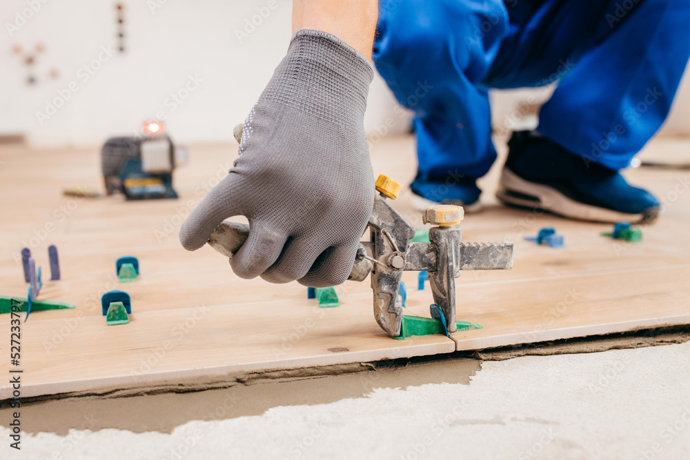 Close up hands of repairman in grey gloves and special uniform laying ...