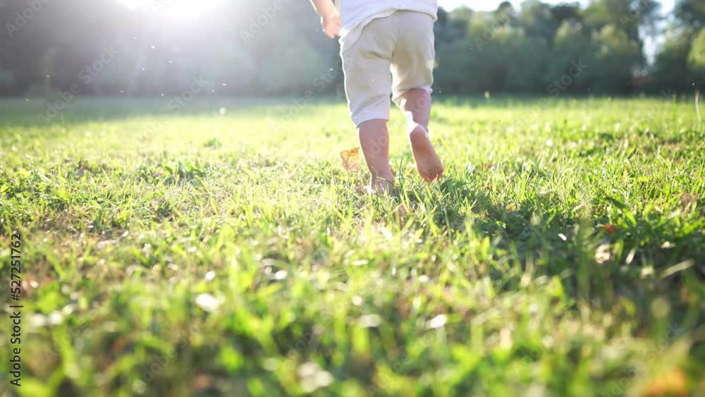 baby running in the park with bare feet. close-up of the kid leg runs ...