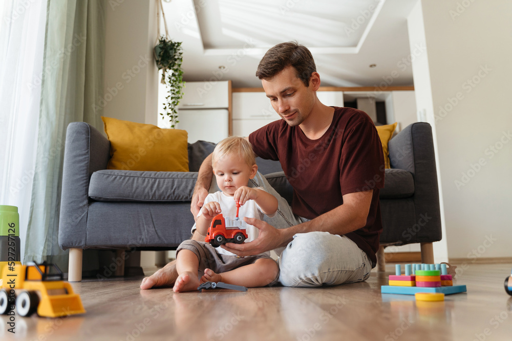 Caring dad and child son play with car toy sitting on floor at home ...
