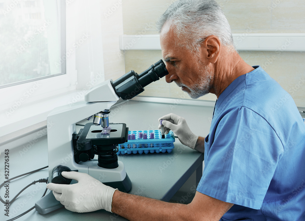 Professional male scientist looking in microscope while working on ...
