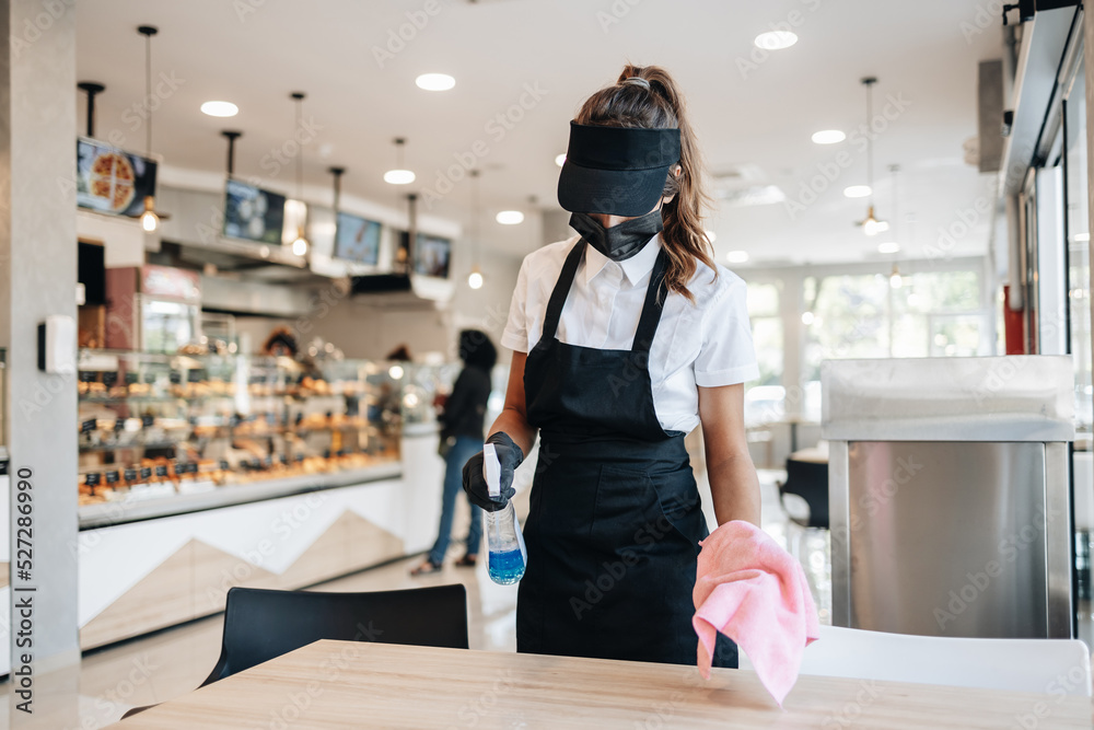 Beautiful woman working bakery or fast food restaurant. She is cleaning ...