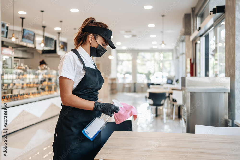 Beautiful woman working bakery or fast food restaurant. She is cleaning ...