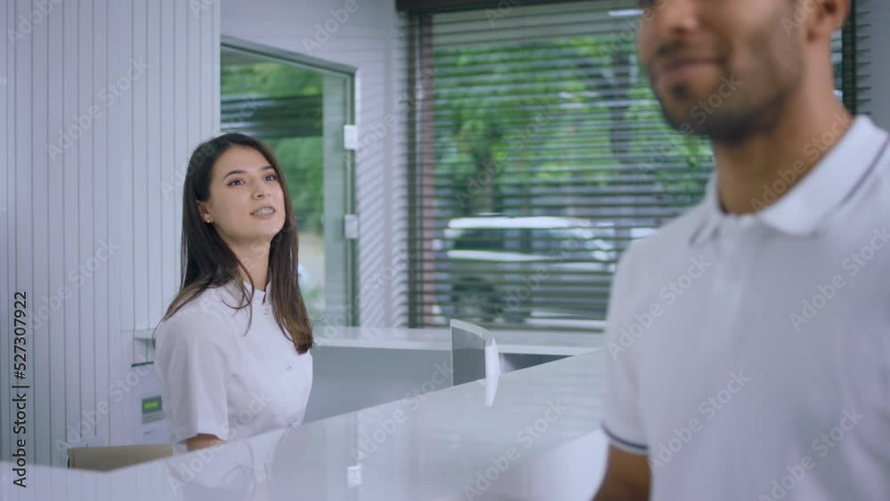 At reception desk beautiful lady medical assistant giving the results ...