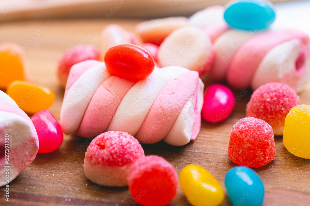 Balas de goma e doces variados e coloridos sobre uma tábua de madeira ...