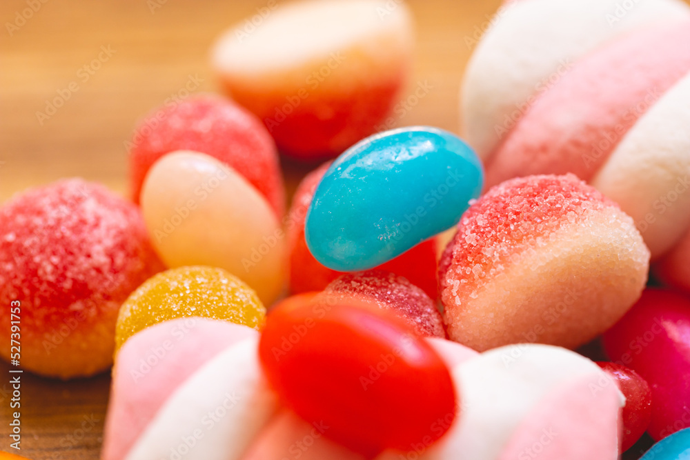 Balas de goma e doces variados e coloridos sobre uma tábua de madeira ...