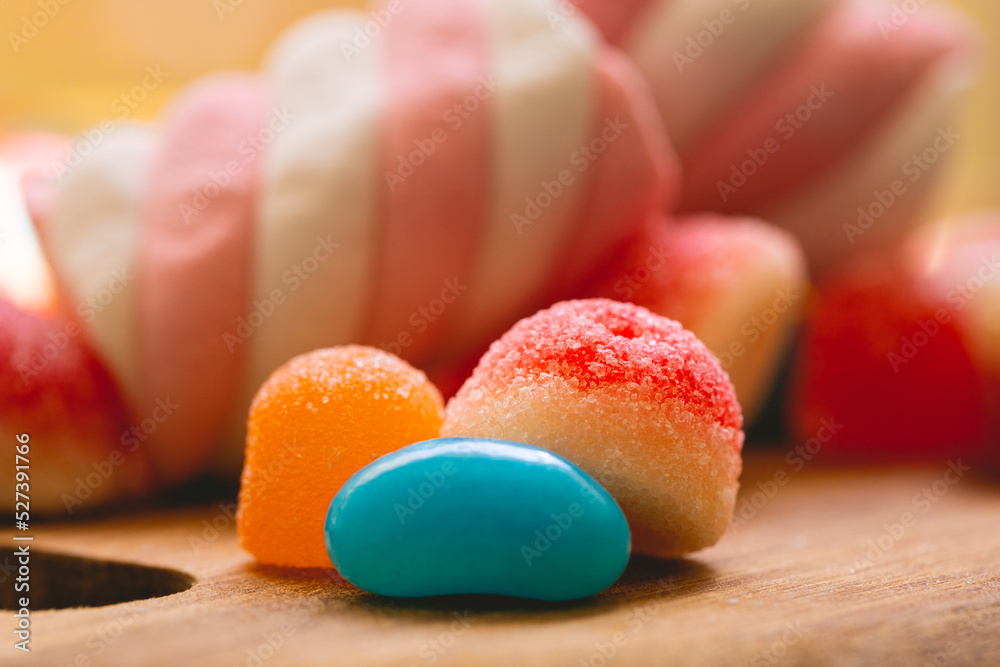 Balas de goma e doces variados e coloridos sobre uma tábua de madeira ...