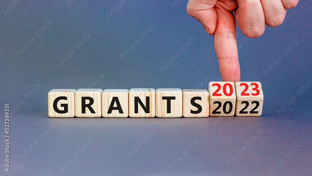 Planning 2023 grants new year symbol. Businessman turns a wooden cube ...
