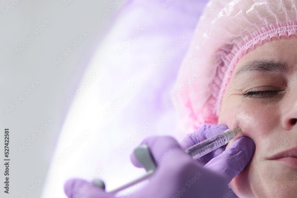Injection of a filler for the face. Cosmetic procedures. The beautician ...