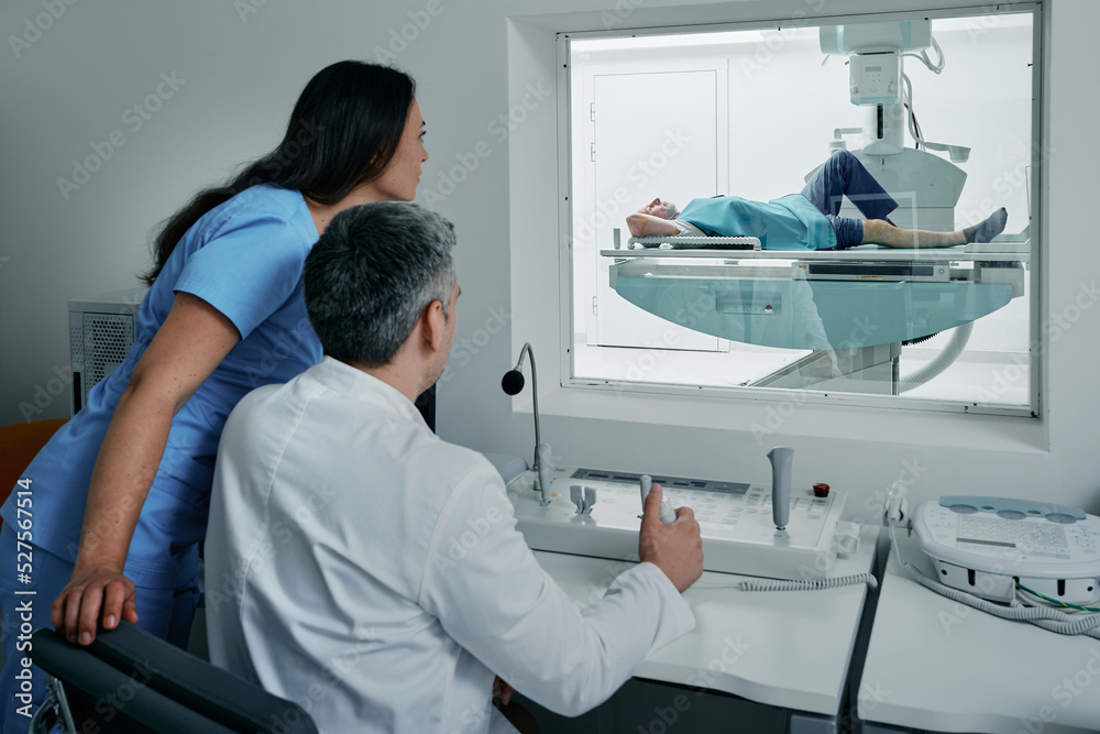 Radiologist with nurse control X-ray process from their office behind ...
