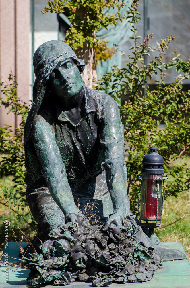 La statua bronzea di una donna dolente inginocchiata su una tomba del ...