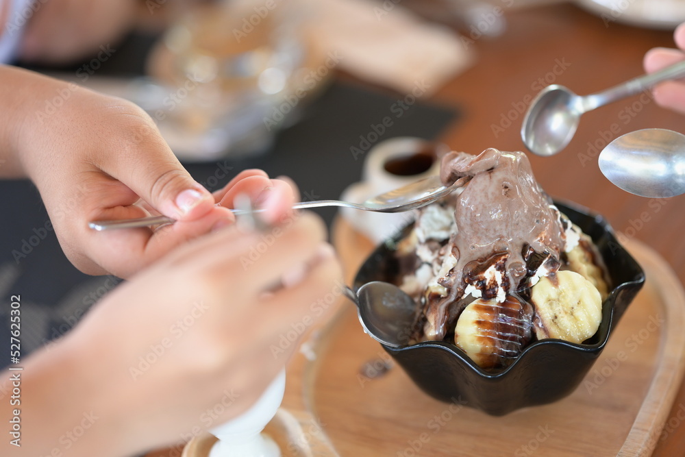 Children scramble in a chocolate sundae with spoons as it melts. Ice ...