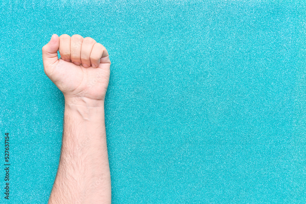protesting man hand fist from below with bright aquamarine background ...