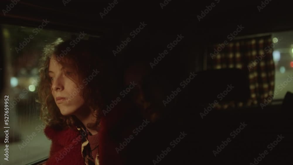 Two young girlfriends cuddling while riding in back seat of taxi and ...