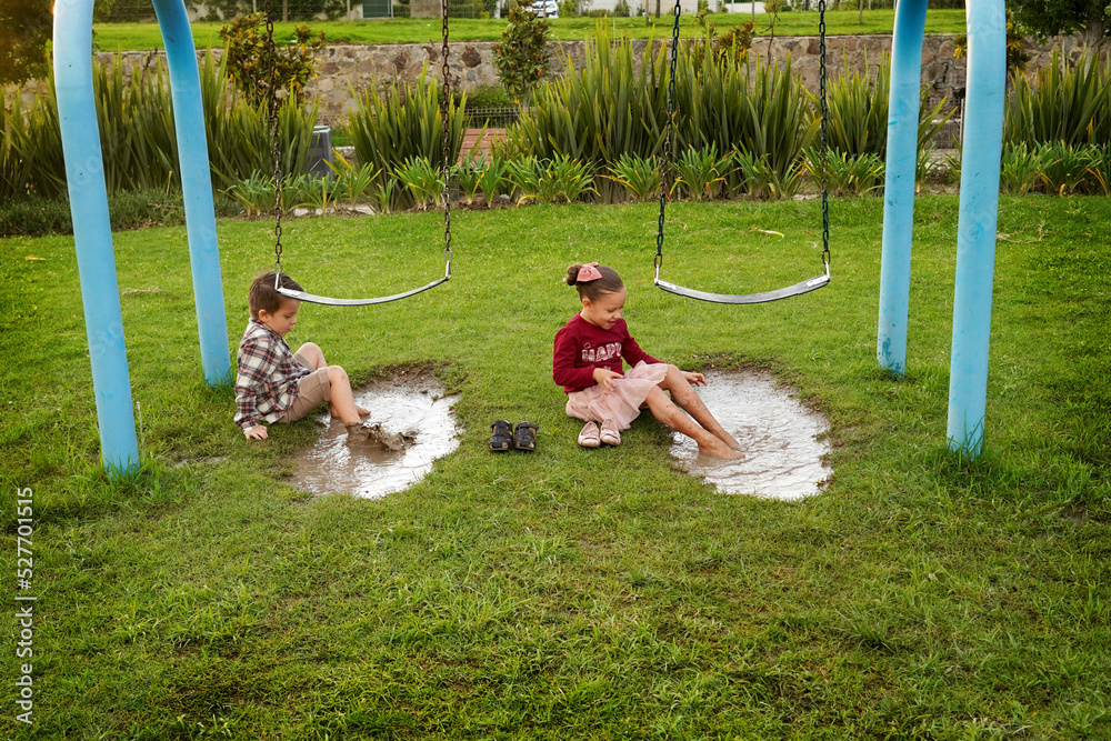 Niños felices sentados jugando en un charco de agua con el lodo ...