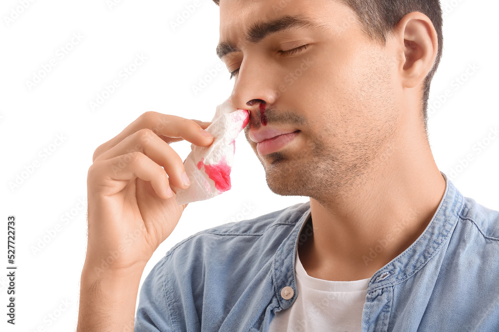Young man wiping nosebleed with tissue on white background, closeup ...