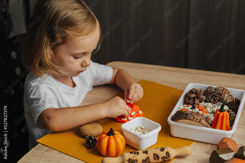 A little girl playing with autumn natural materials and play dough ...