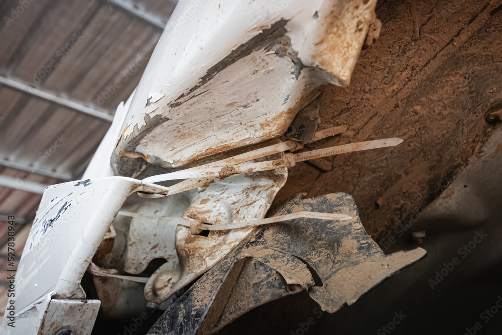 Using cable ties to fasten the front bumper parts of a car that has an ...