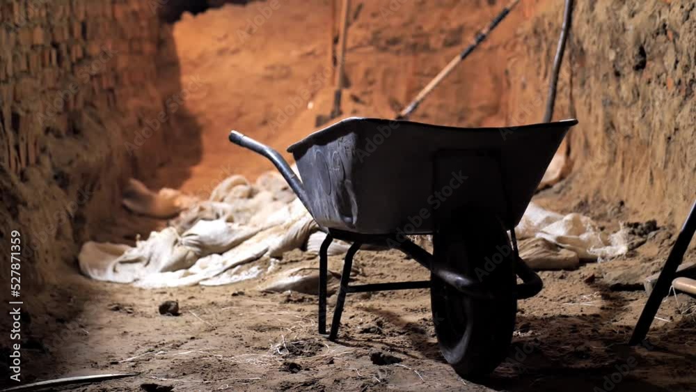 A one-wheeled wheelbarrow is in a large pit. Removal of land during the ...