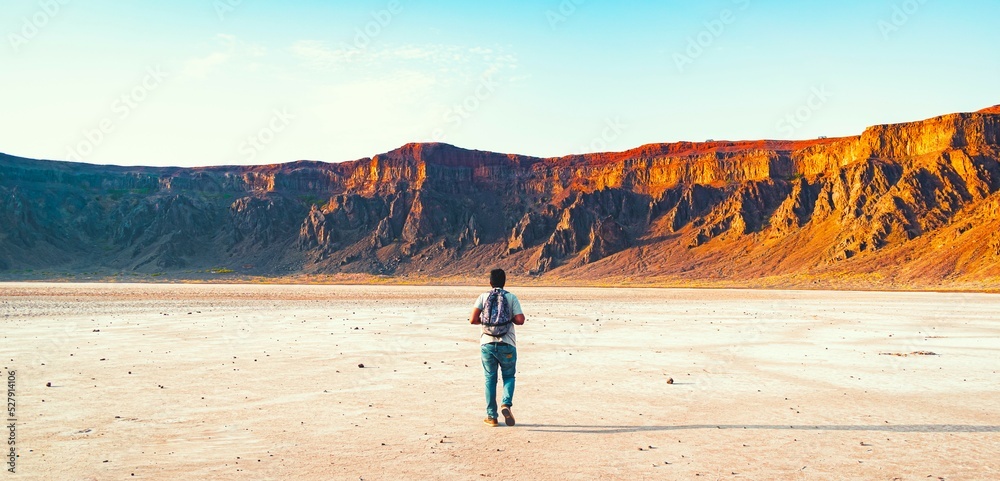 Person walking in a volcanic crater. An image from Wahbah Crater, Saudi ...