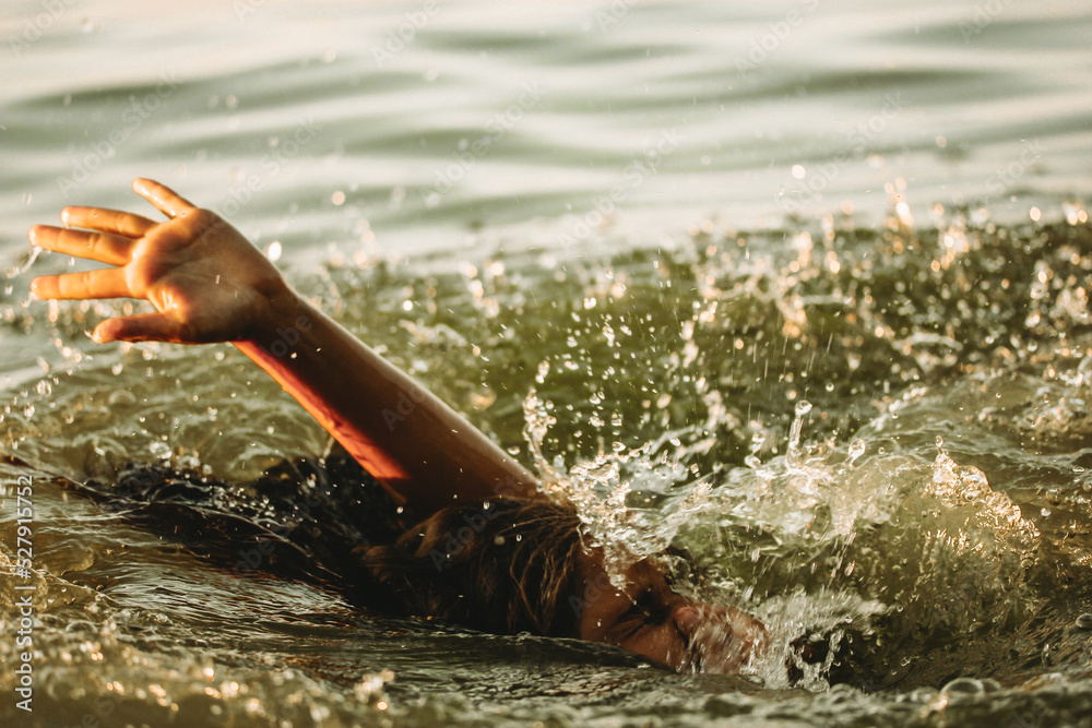 A hand peeks out from under a water. A drowning person, victim needs ...
