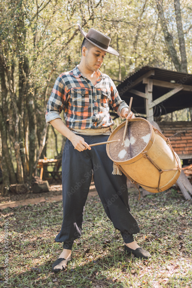 Ethnic musician in hat playing drum on lawn Stock Photo | Adobe Stock