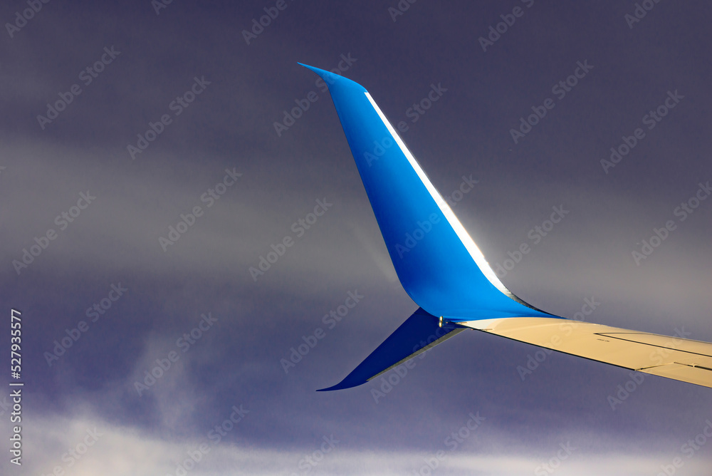 Airplane wing. Blue wing tip of the aircraft against the blue sky with ...