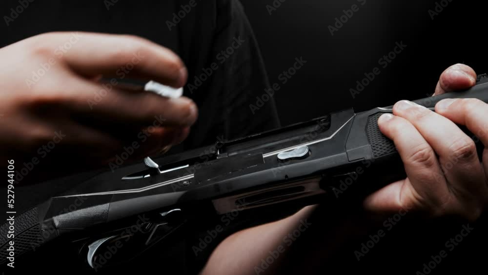 Close-up: a man in a black T-shirt on a black background loads a ...