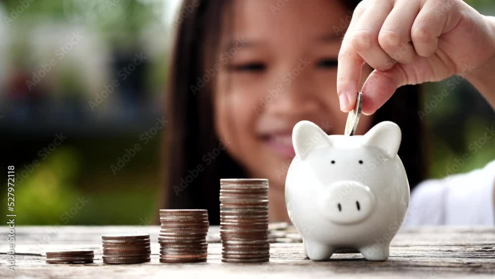 Saving Money Concept. Happy Asian child girl save money by putting ...