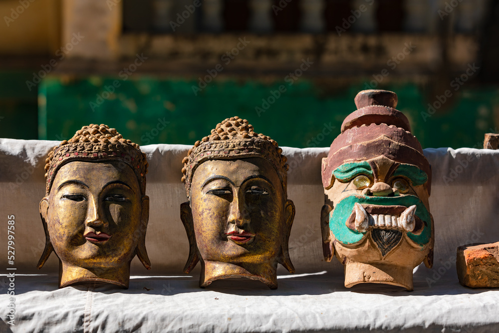 Three masks on an outdoor market stall in front of a temple in Bagan ...