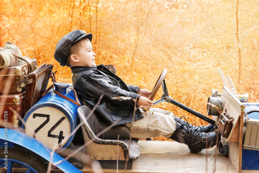 Young happy racer. Little boy in the guise of a racer started an old ...