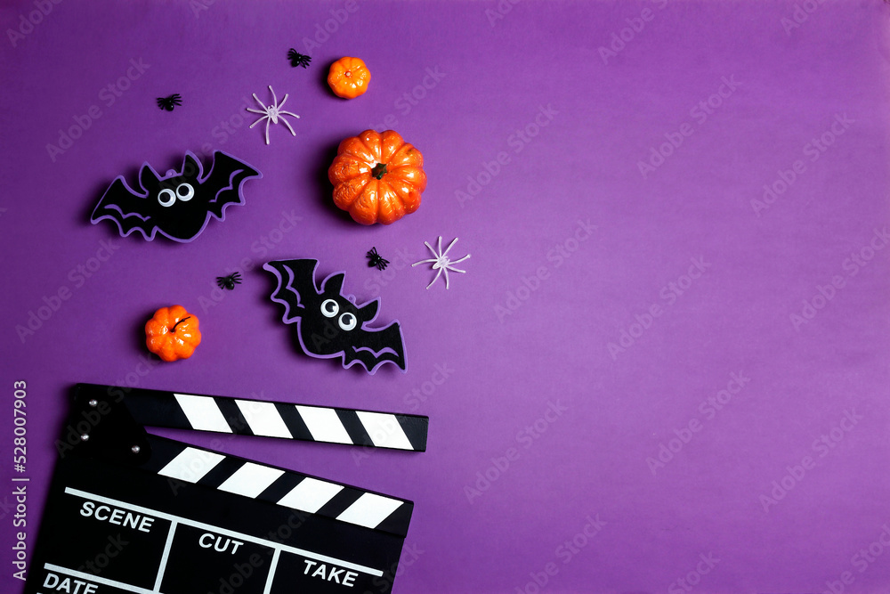 Movie clapper board with Halloween decorations on a purple background ...