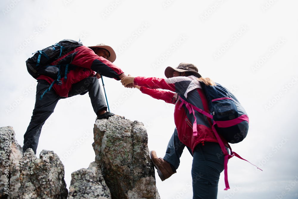 Person hike friends helping each other up a mountain. Man and woman ...