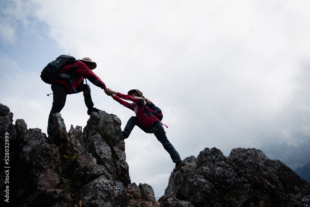 Person hike friends helping each other up a mountain. Man and woman ...