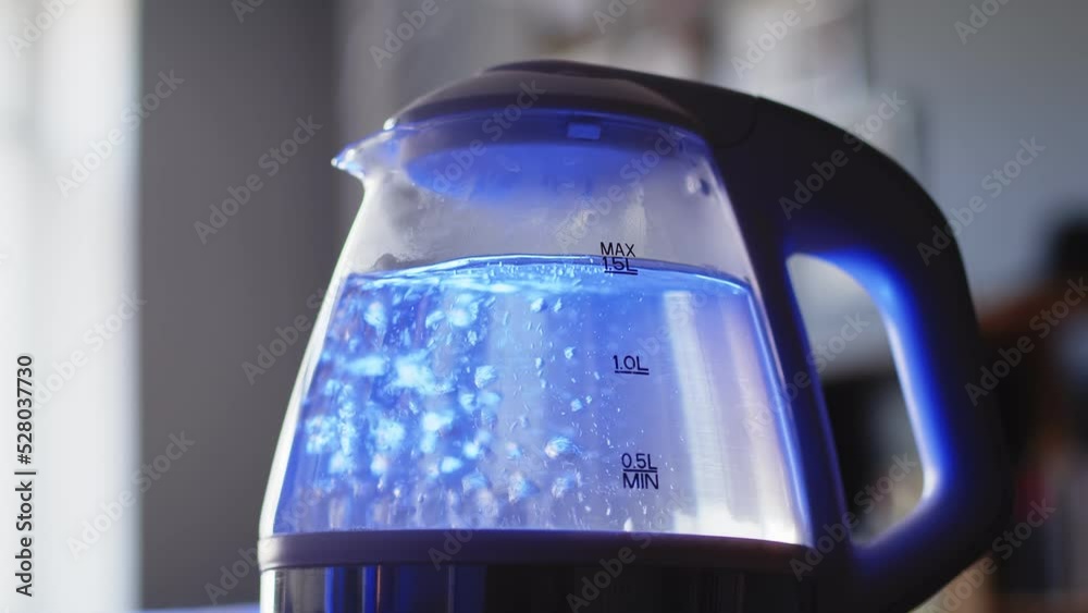 Stockvideon Closeup of electric kettle boiling water. The hand closes ...