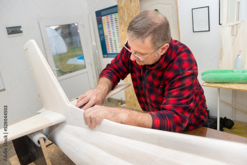 Carpenter and modeler making model of the airplane in his workshop ...