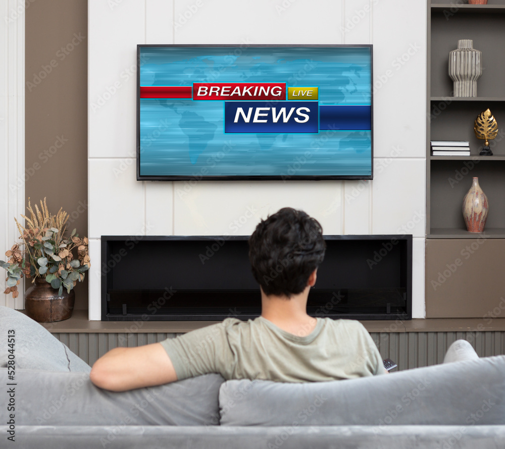 Back view on excited man sitting on the couch and watching breaking ...