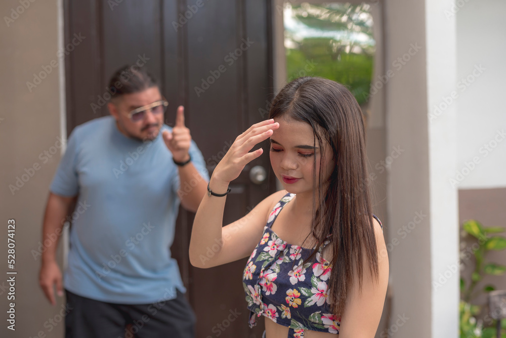 A teenage girl covers her face as she feels shy being scolded by her ...