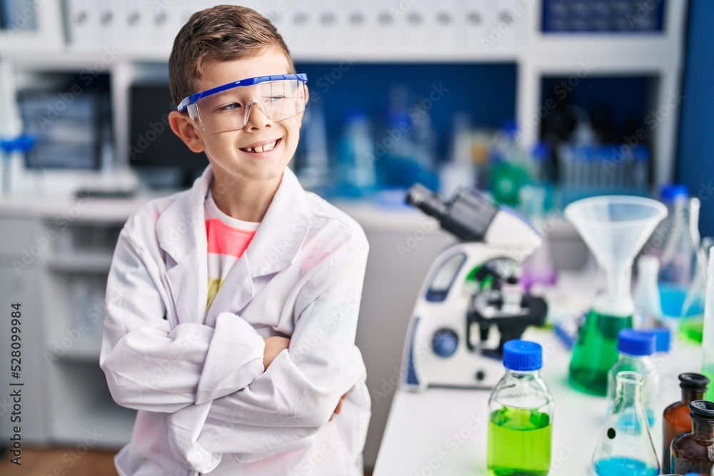 Blond child wearing scientist uniform sitting with arms crossed gesture ...