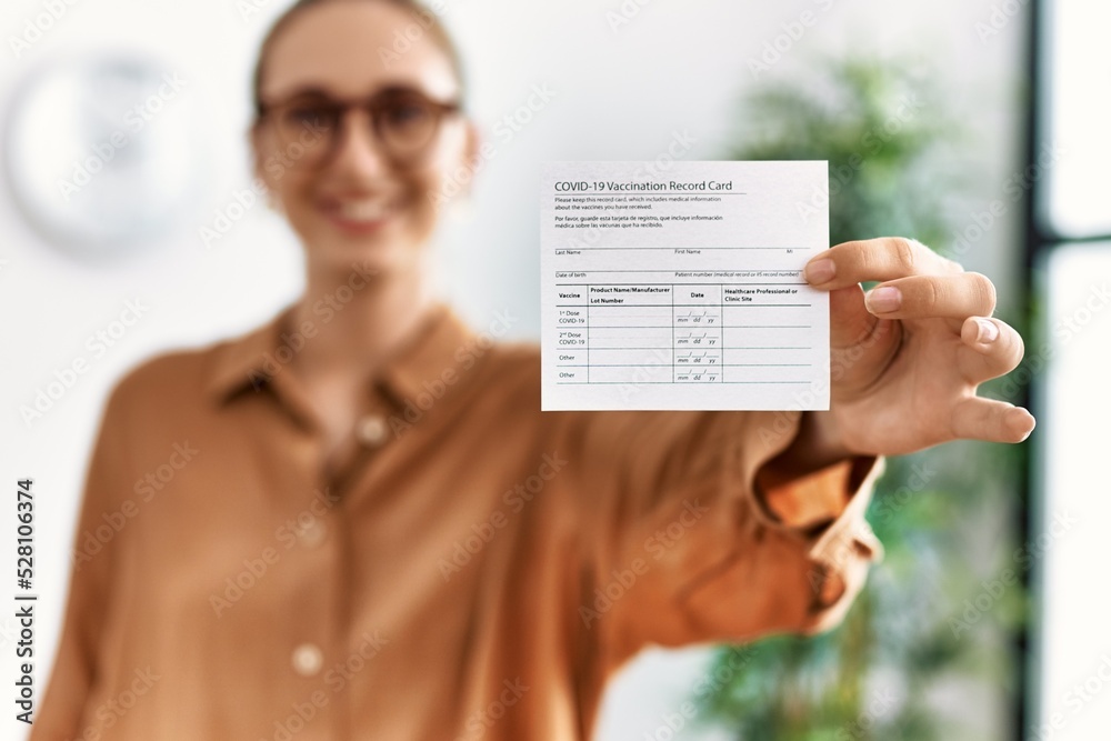 Young blonde woman smiling confident holding covid vaccination record ...