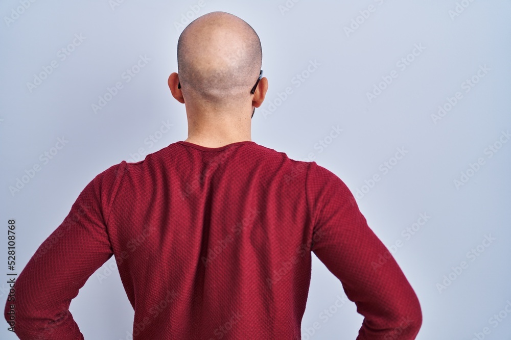Young bald man with beard standing over white background wearing ...