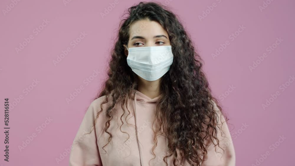 Portrait of unhappy young woman wearing medical face mask gesturing ...