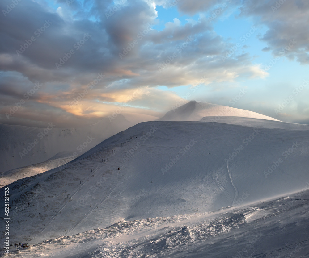 Snow covered mountain slope in last evening sunlight. Magnificent windy ...