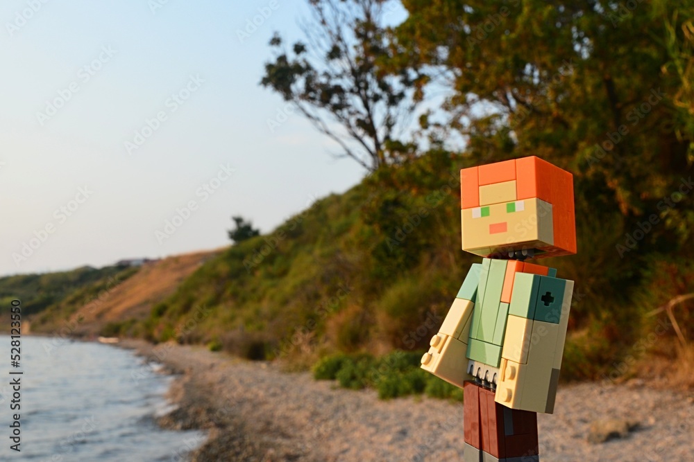 LEGO Minecraft Alex sunbathing in evening sunshine on pebble beach in ...