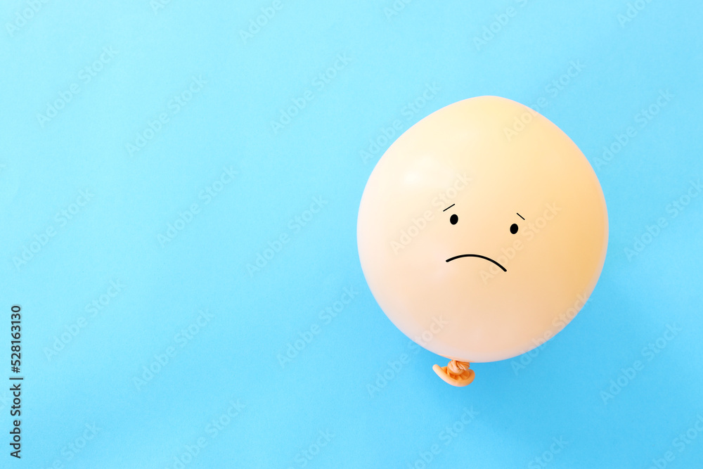Top view image of balloon with sad face over blue background. Concept ...