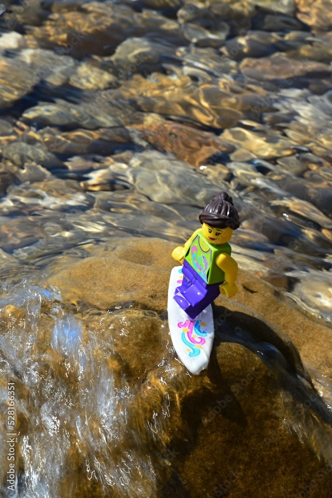 LEGO City female surfer standing with surf on shoreline rock on pebble ...