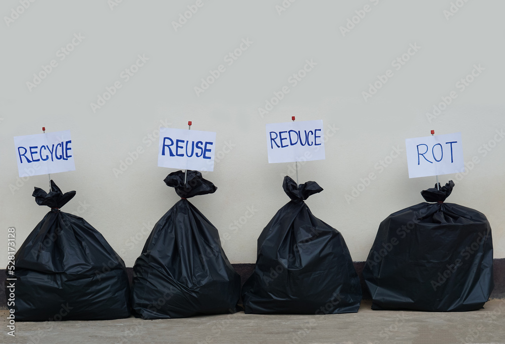 Paper signs with words "RECYCLE" "REUSE" "REDUCE" "ROT" on black ...