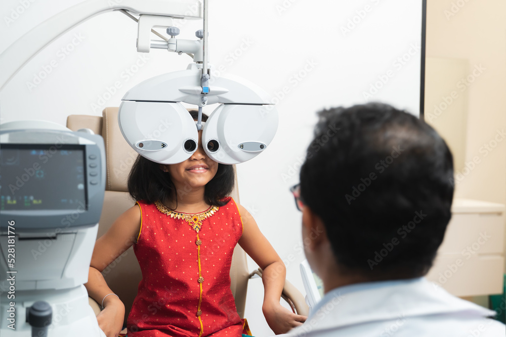 Happy Indian child girl doing subjective refraction with phoropter ...