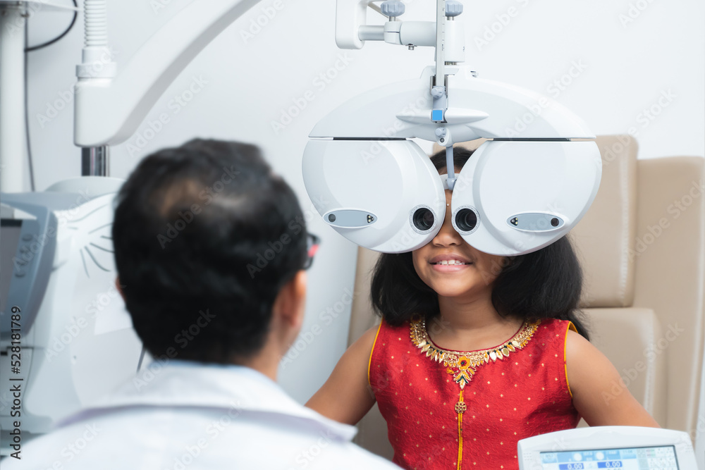 Happy Indian child girl doing subjective refraction with phoropter ...