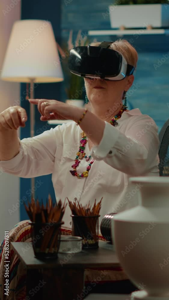 Vertical video: Senior woman using vr glasses with augmented reality to ...